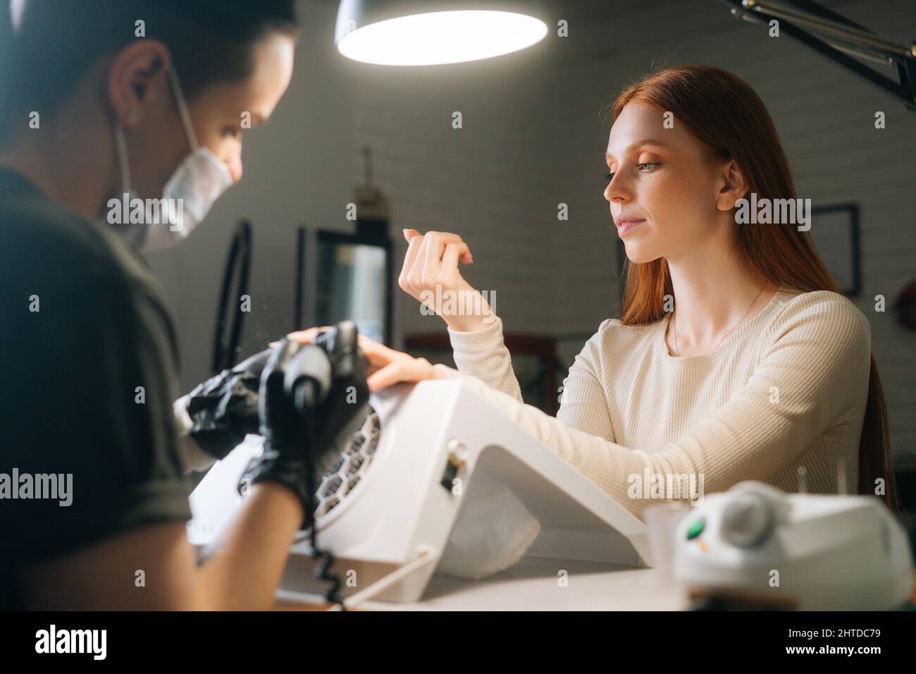 Side view of attractive young woman examining treated nails and ...