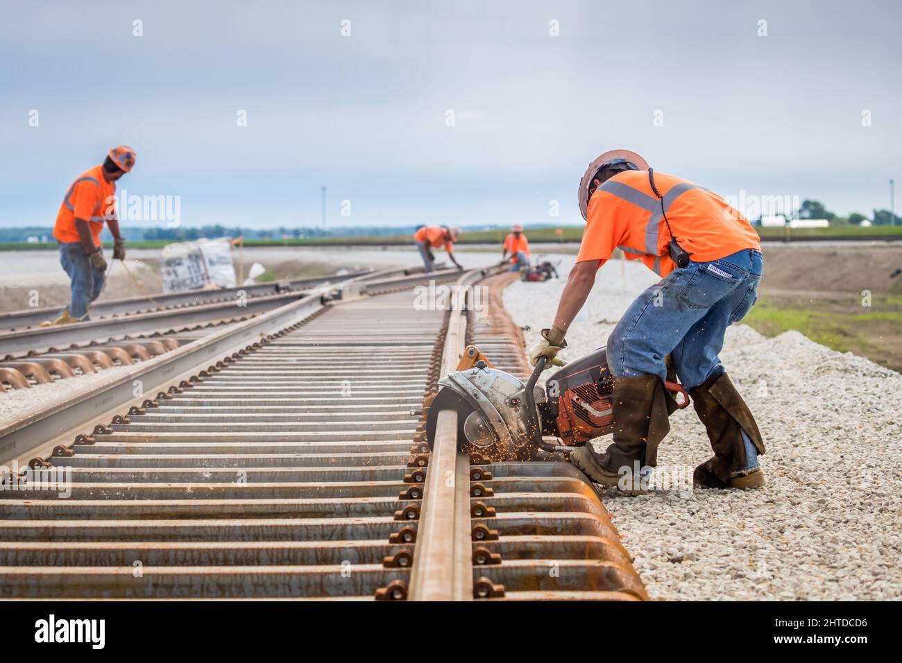 Workers in the process of railroad track construction - rail saw with ...