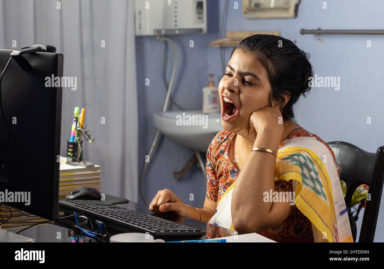 Indian woman in saree working on computer at home and yawning Stock ...