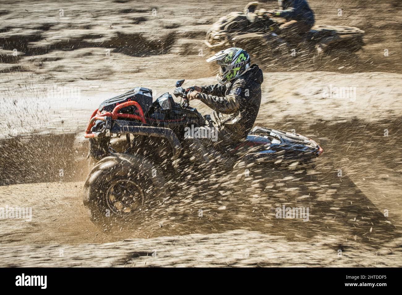 Side view of a man riding on a Can-Am Outlander on a muddy track during ...
