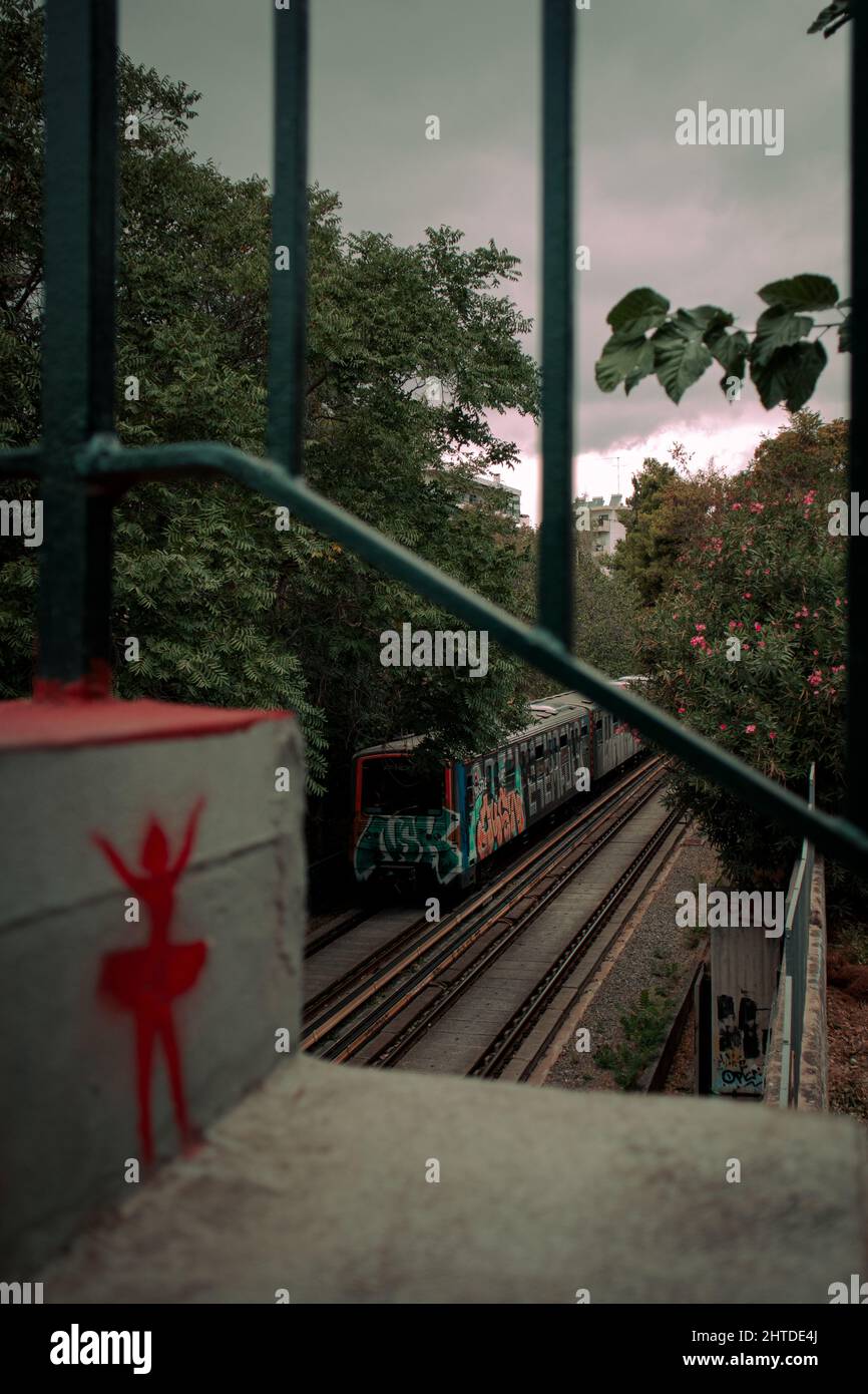 Vertical shot of train behind stairs with metal fence in Athens, Greece ...