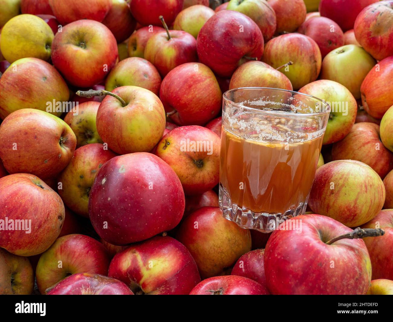 Glass with apple juice on a stack of apples Stock Photo - Alamy