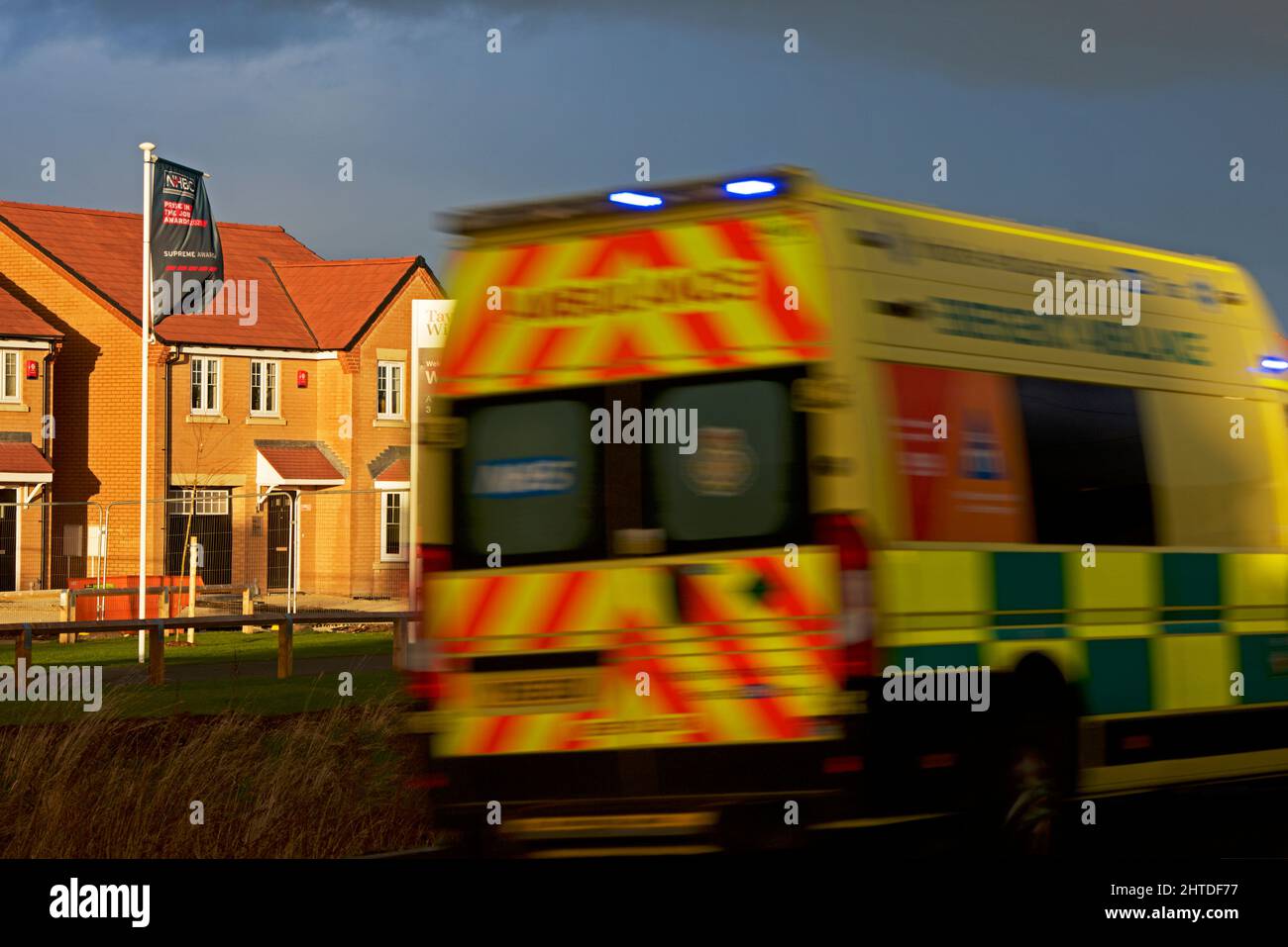 Ambulance passing houses built by Taylor Wimpey at Whitacres, a new ...