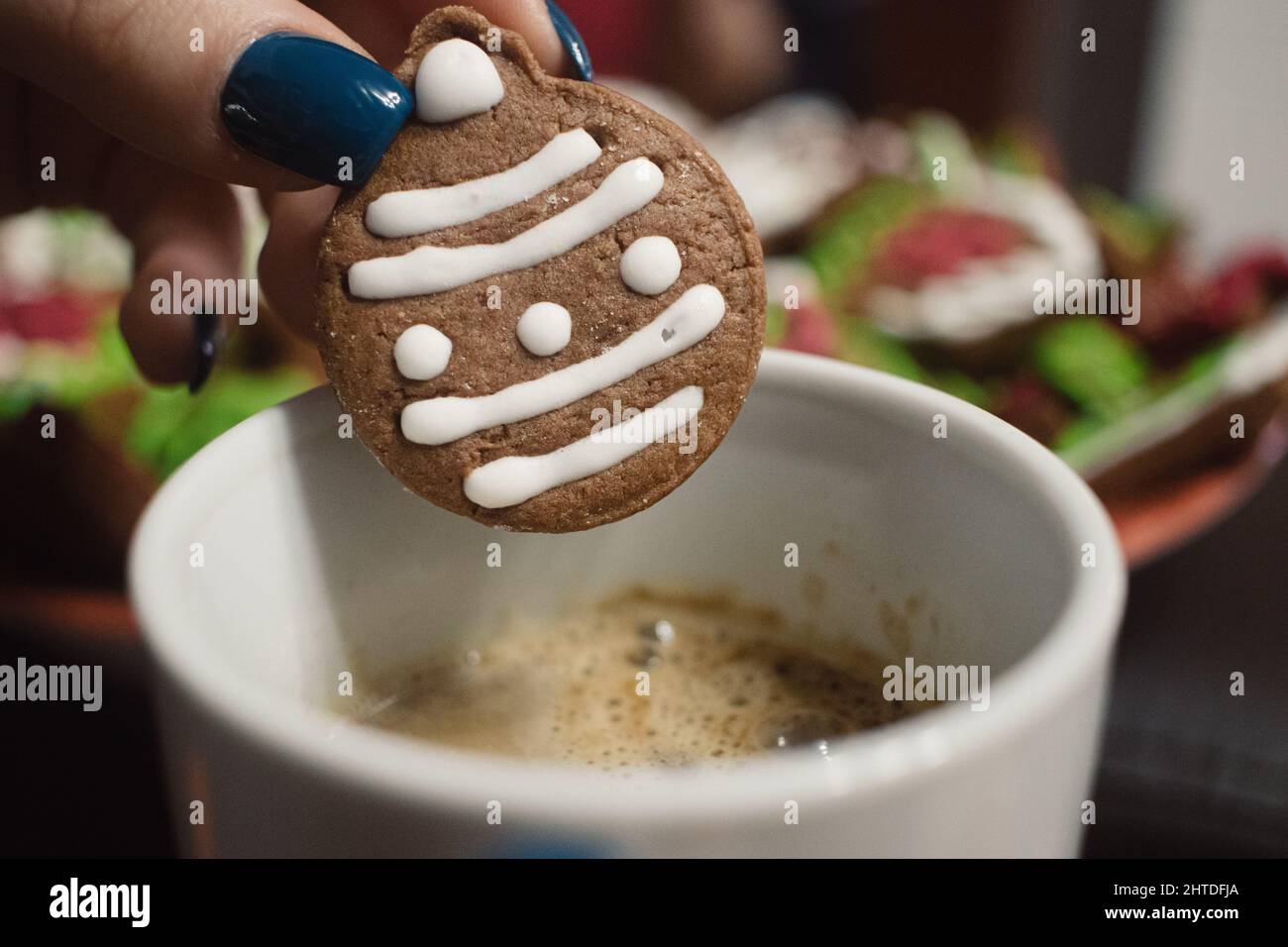 Closeup shot of the female hand dipping a tasty chocolate cookie in the ...