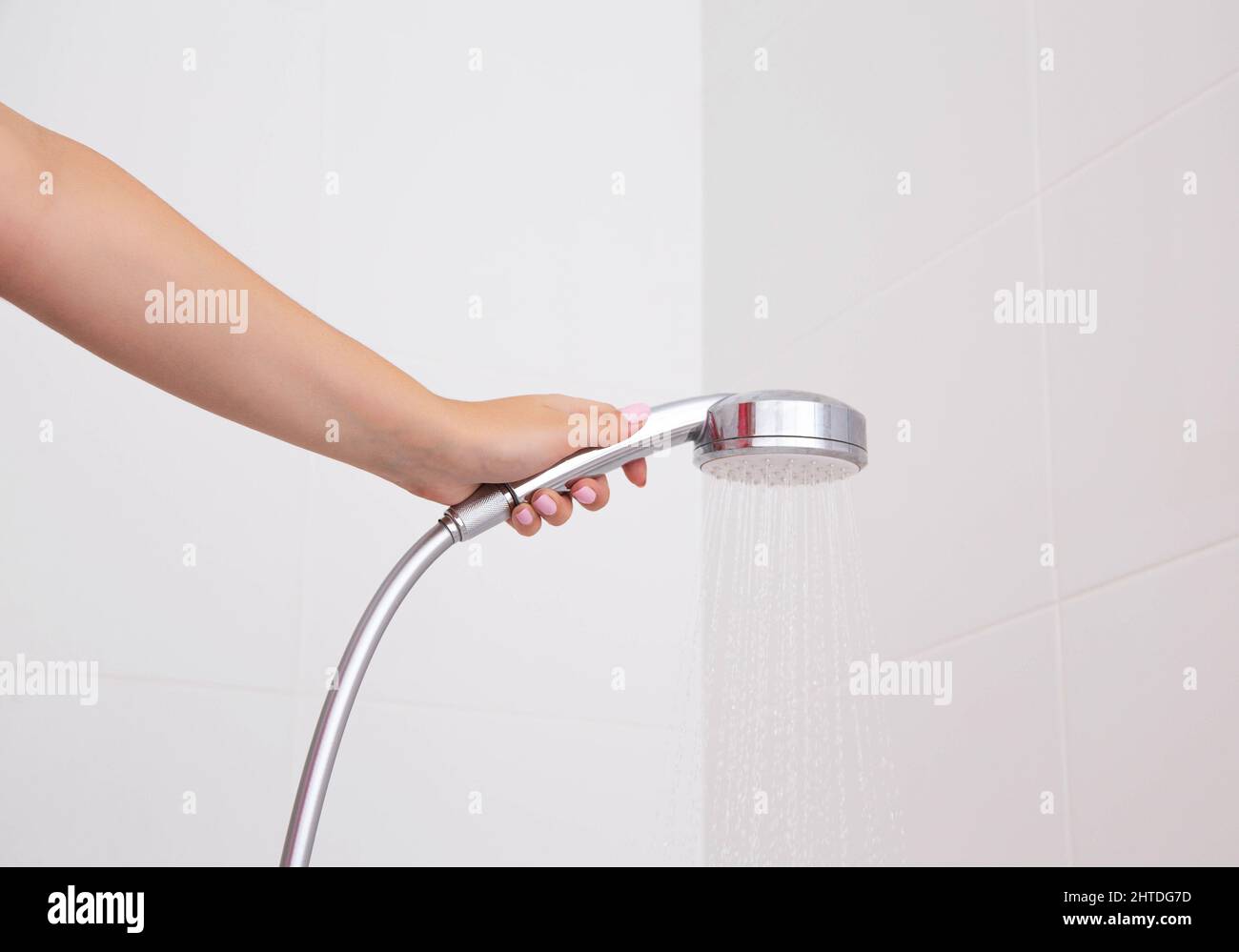 Girl in hand holds a shower in the bathroom against the background of a ...