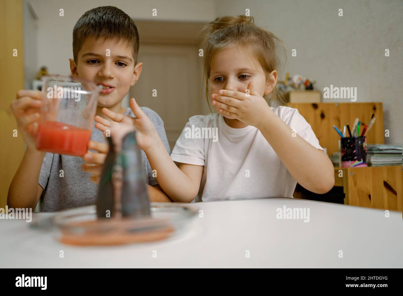 Children, boy and a girl are conducting an experiment with a volcanic ...