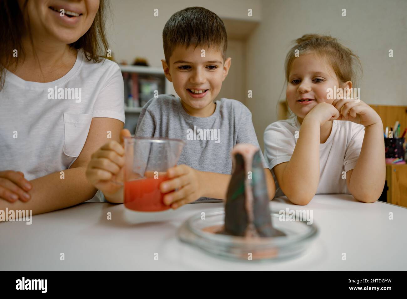 Mom and children at home are conducting an experiment with a volcanic ...