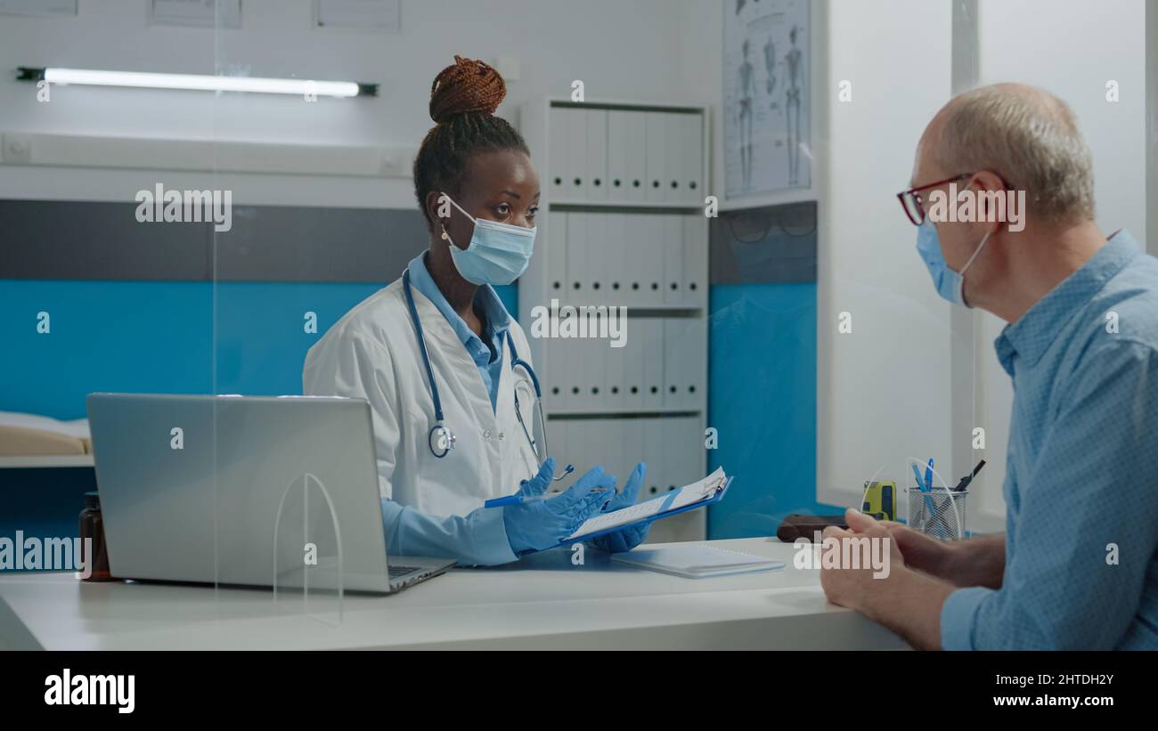 Doctor writing information on checkup papers for elderly man with ...