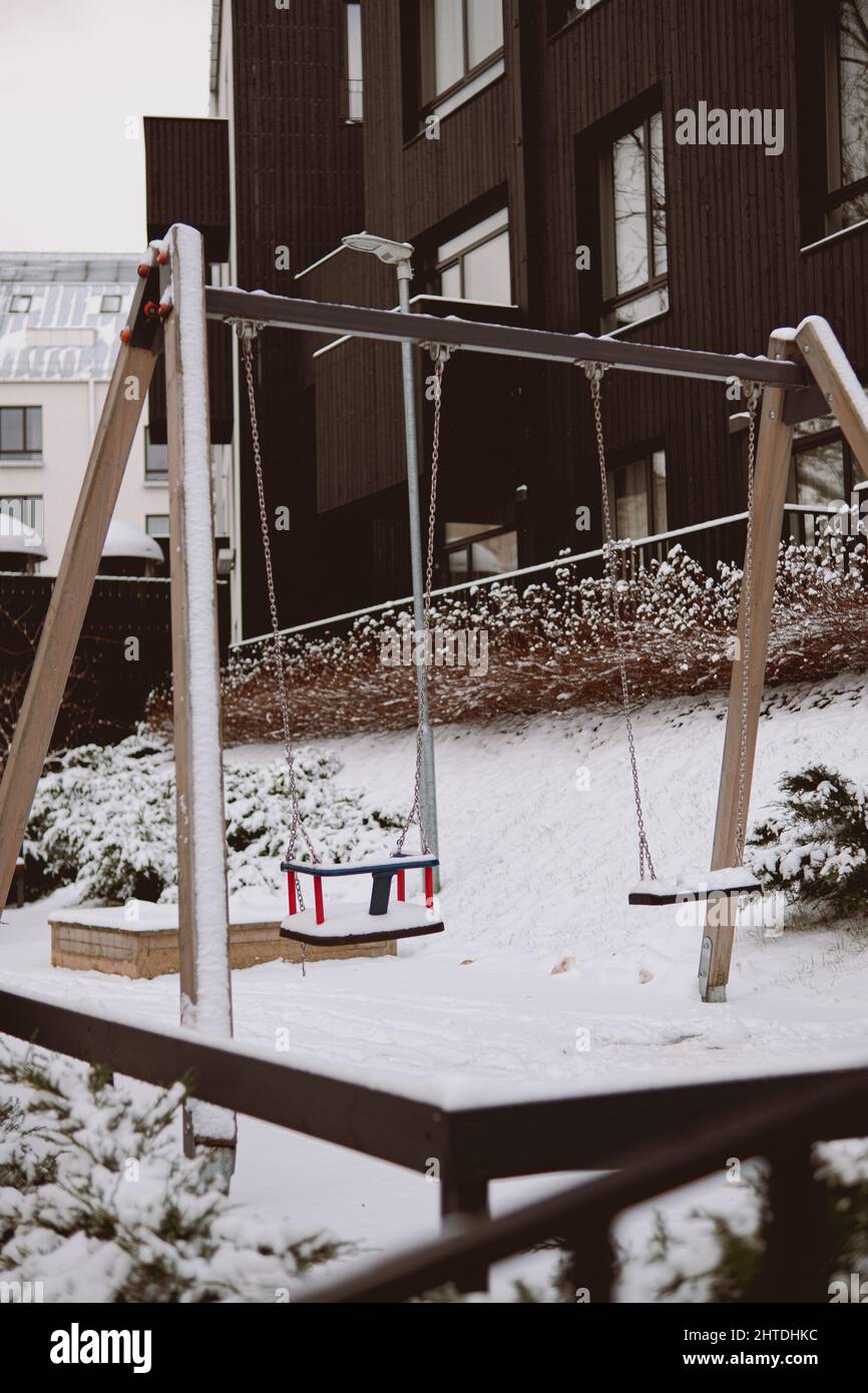 Vertical view of snowy swings in front of a modern, black house Stock ...