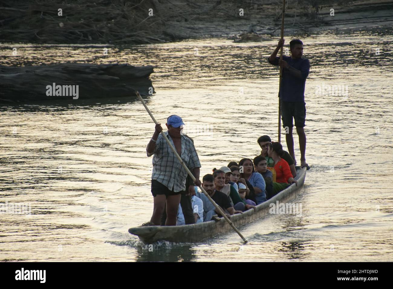 People riding in a dugout canoe, crossing the river. Nepal, Chitwan ...