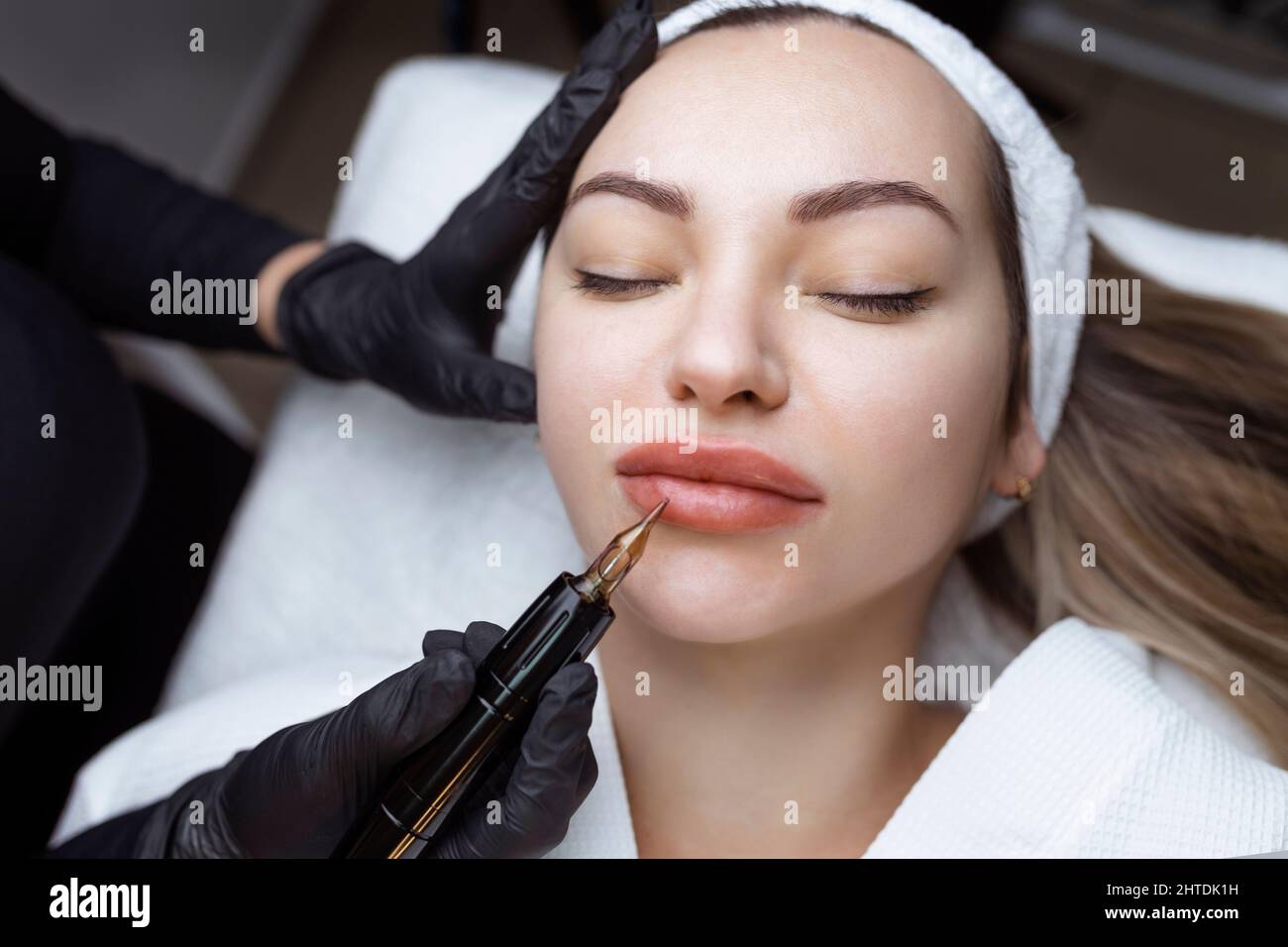 Cosmetologist makes permanent makeup on a woman's face. Specialist ...