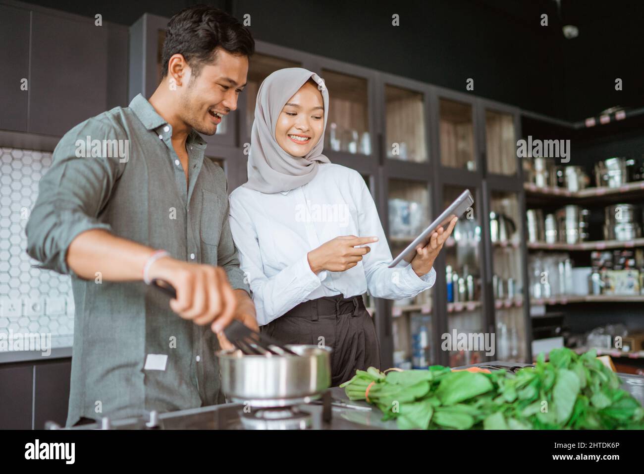 muslim couple cooking together in the kitchen while look at video Stock ...