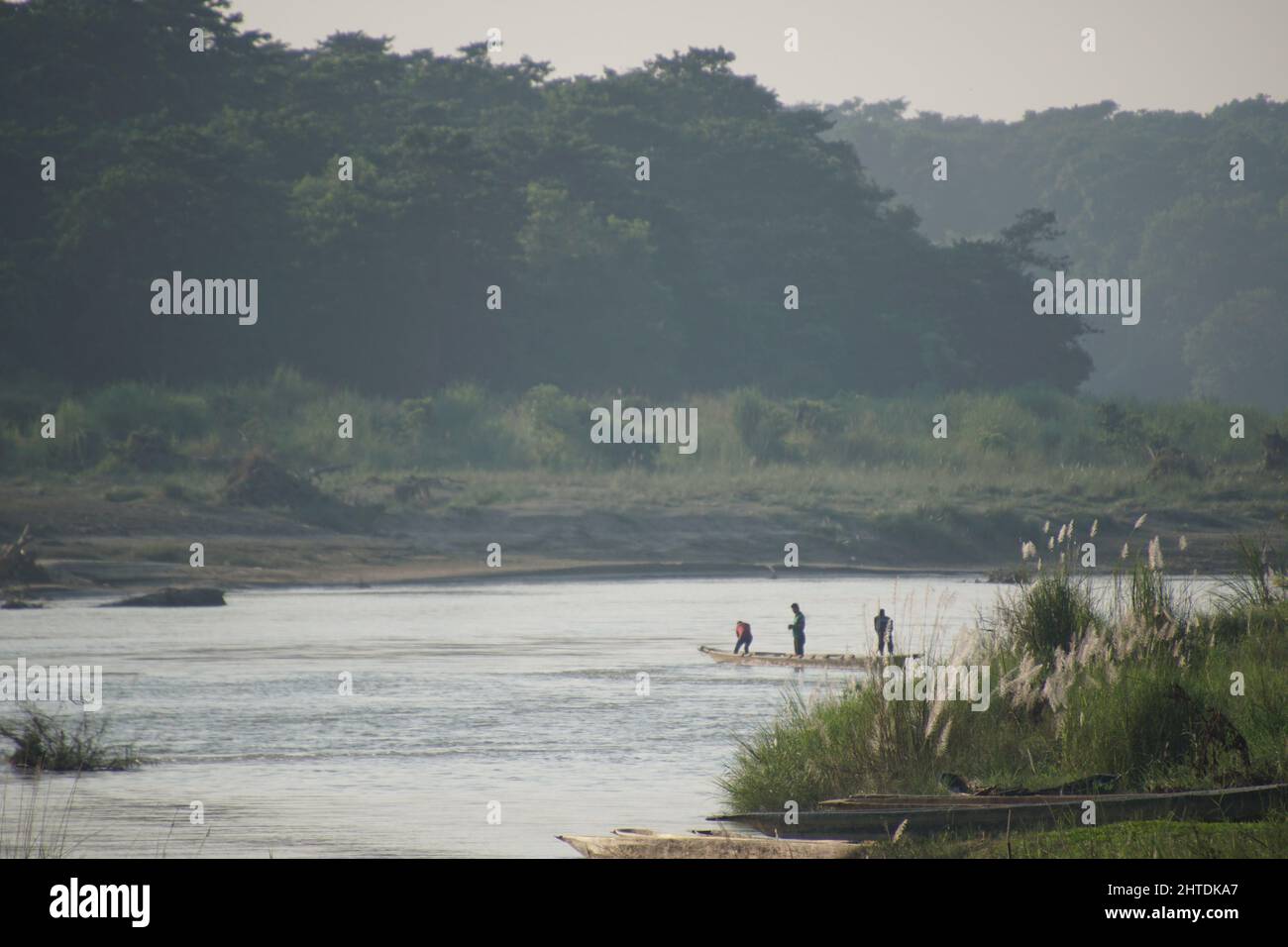 People riding in a dugout canoe, crossing the river. Nepal, Chitwan ...