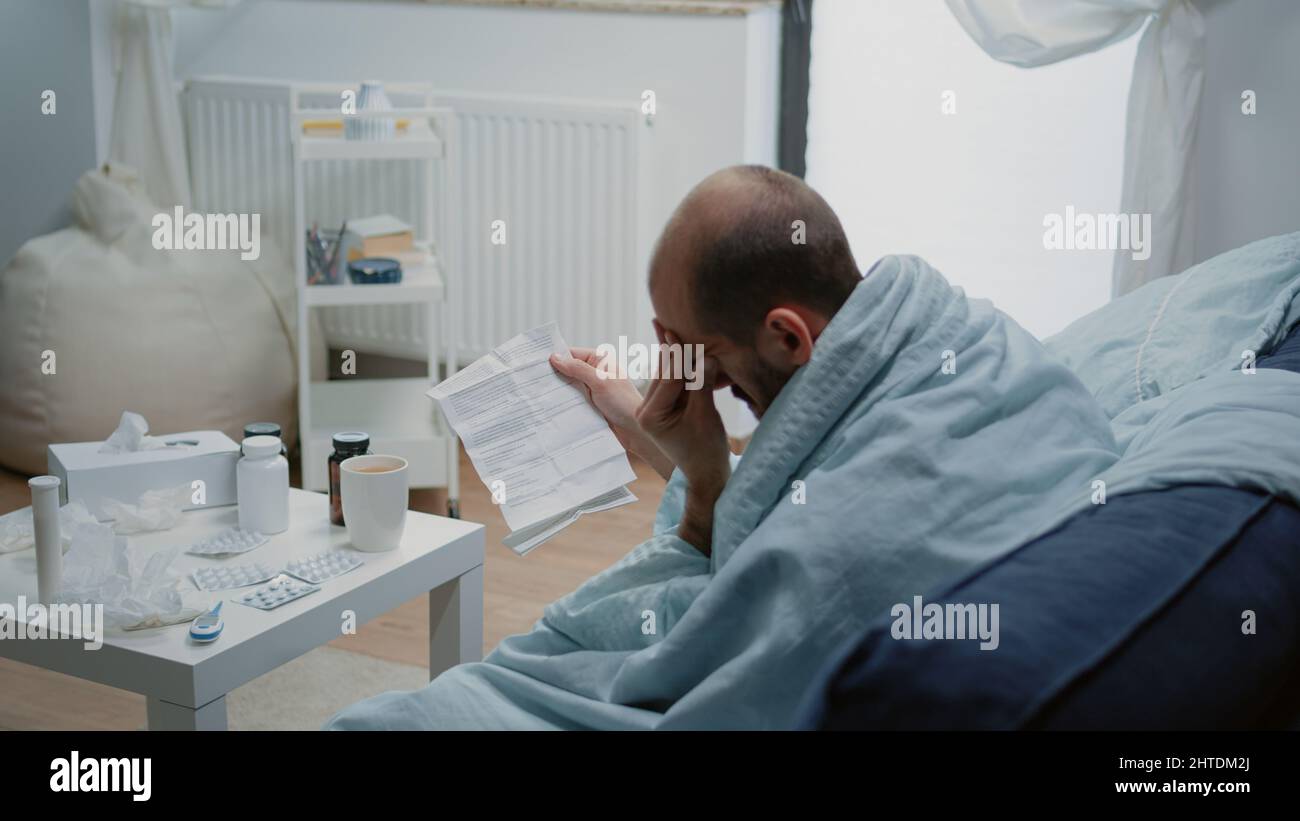 Adult with migraine reading paper with information about medication ...