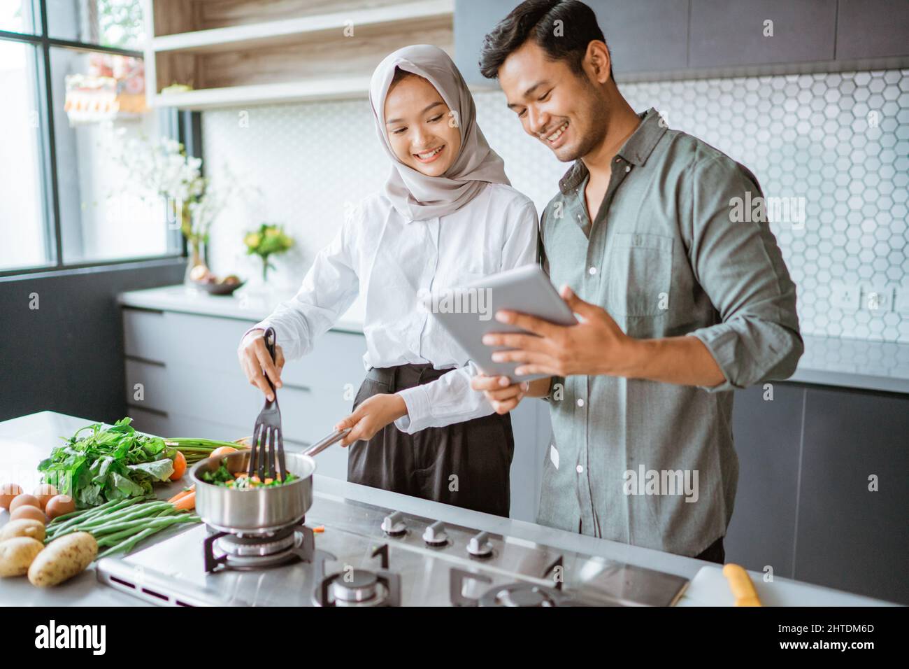 muslim couple cooking together in the kitchen while look at video Stock ...