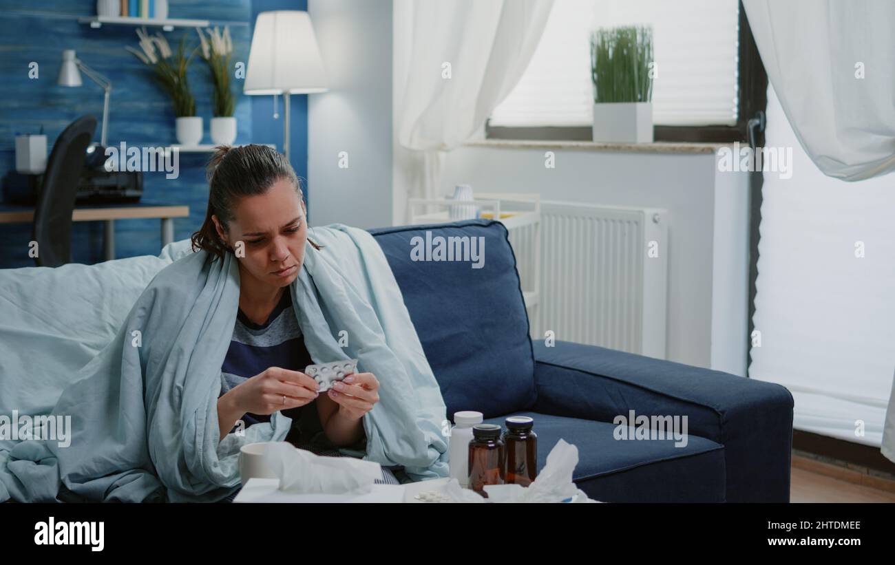 Sick woman looking at bottle of pills and tablets with capsules finding ...