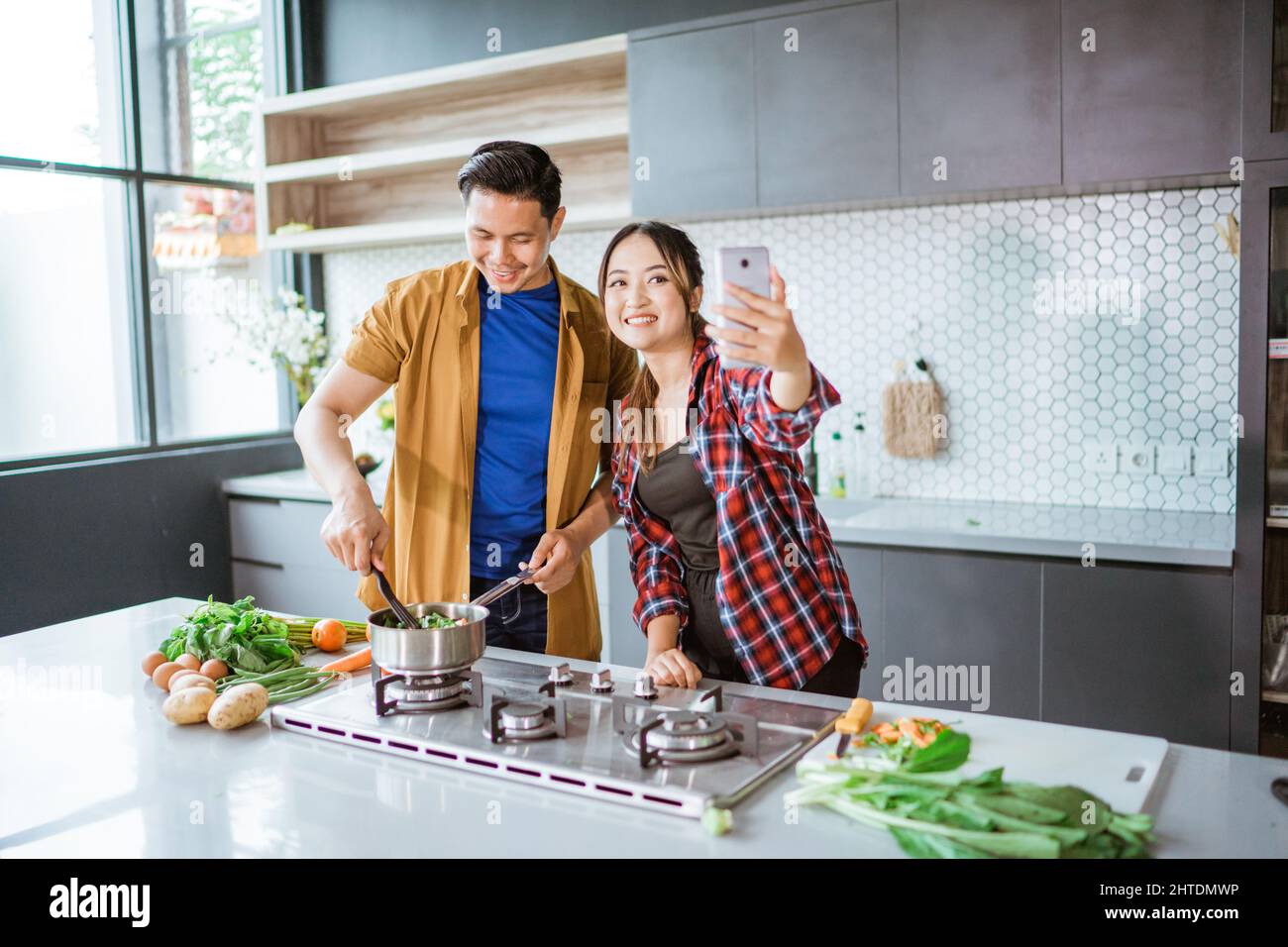 asian couple taking selfie while cooking together in the kitchen Stock ...