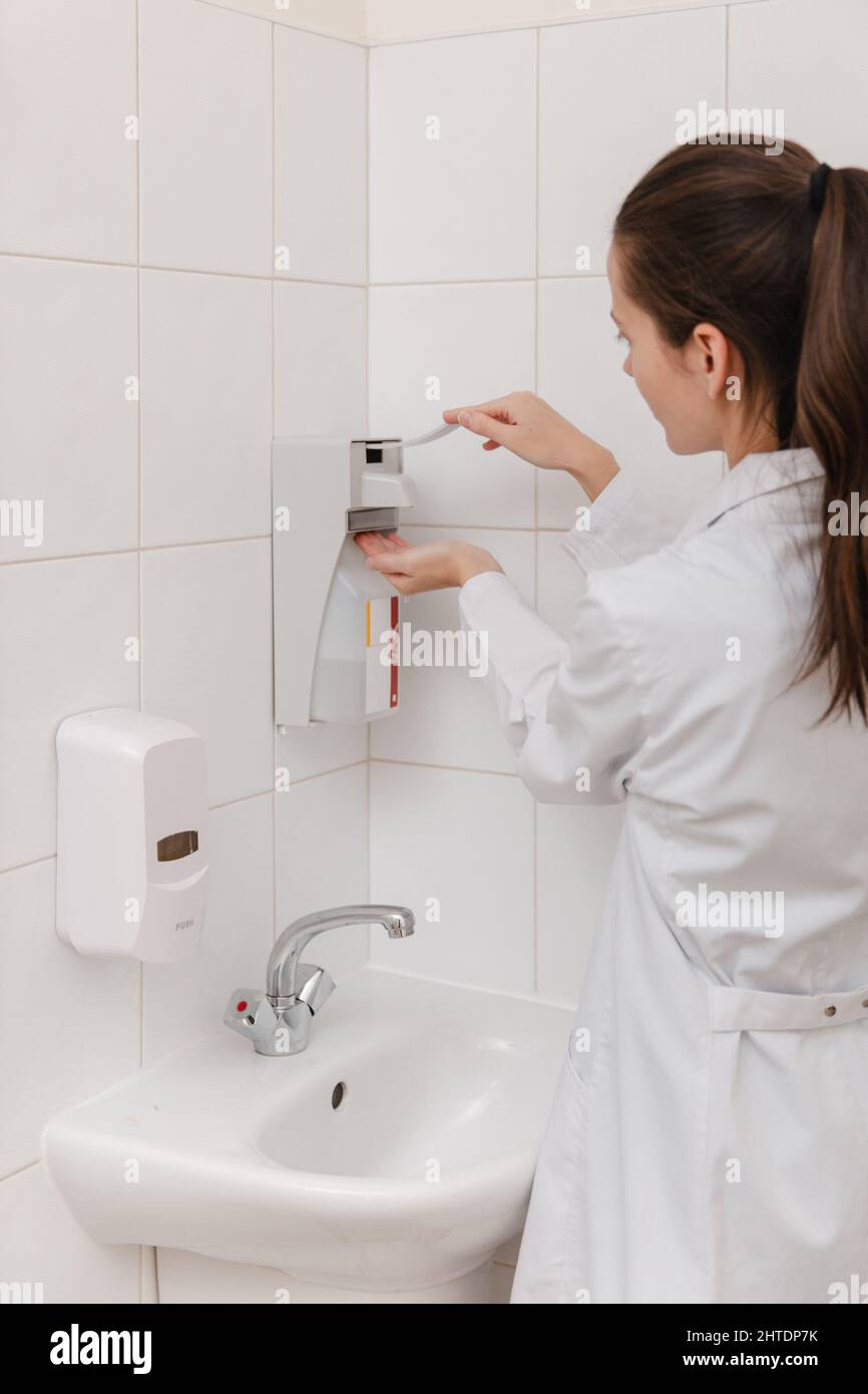 The doctor in white uniform disinfects his hands. Surgeon washing hands ...