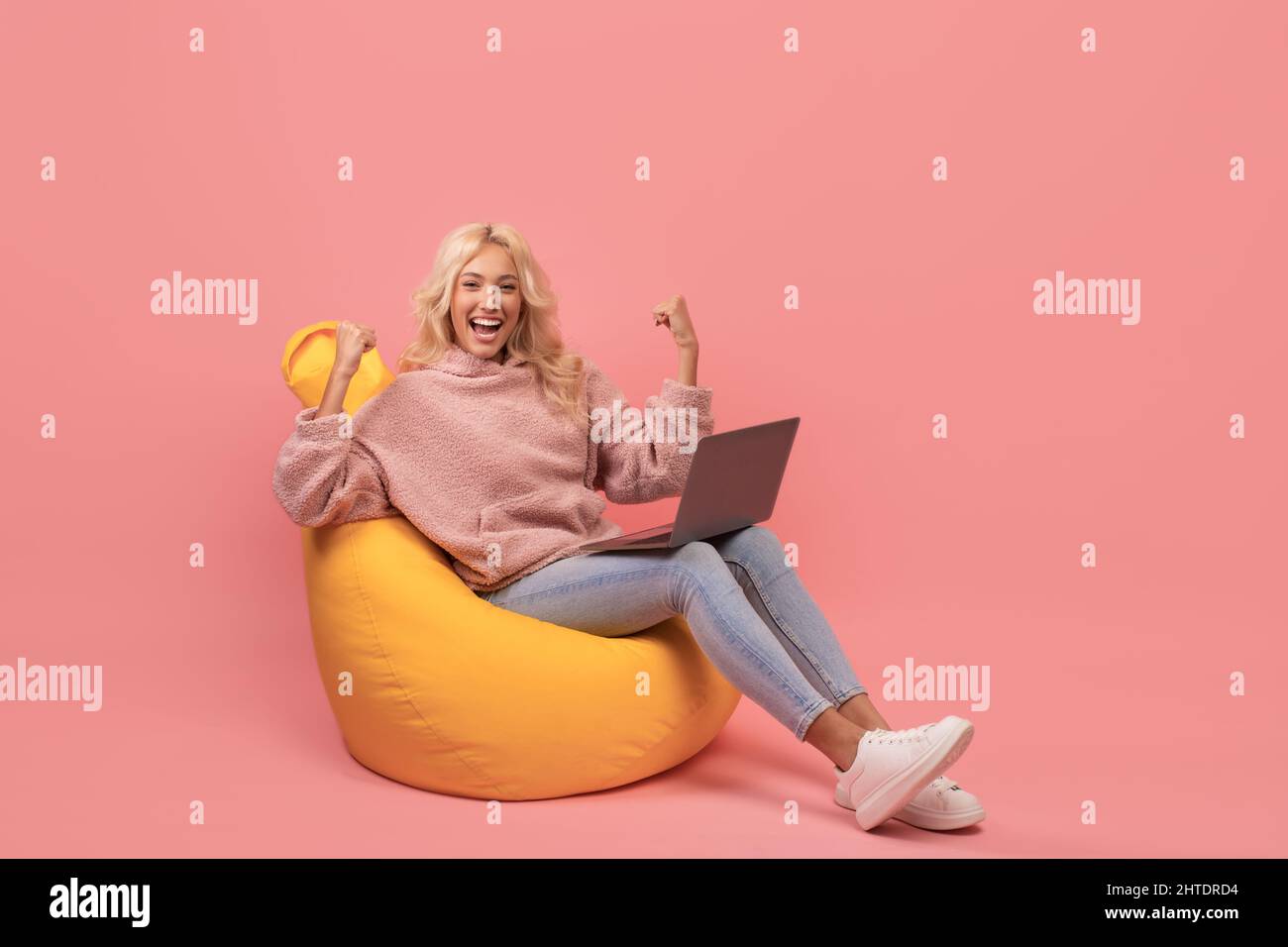 Big win and success concept. Excited lady sitting on beanbag chair with ...