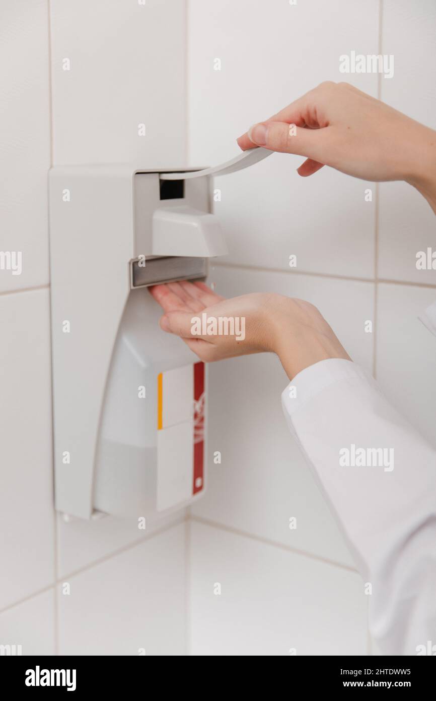 The doctor in white uniform disinfects his hands. Surgeon washing hands ...