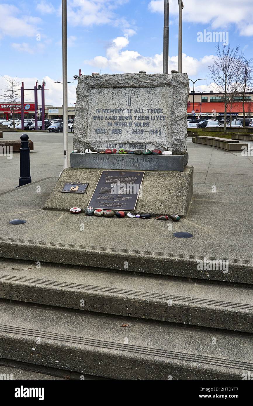 Grey war memorial carved in stone in downtown parking lot with cars and ...