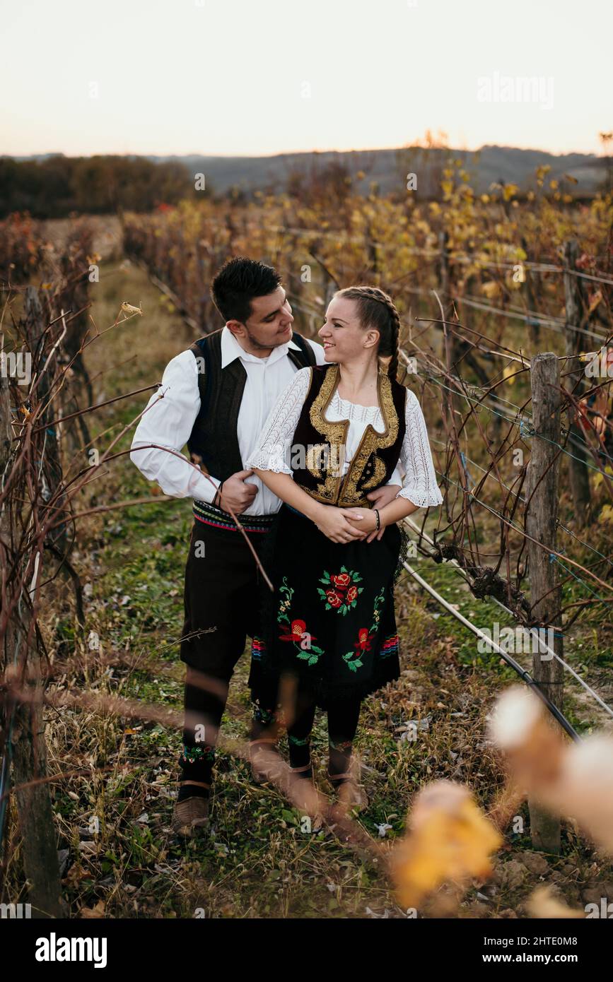 Vertical shot of a Serbian couple in traditional costume having a good ...