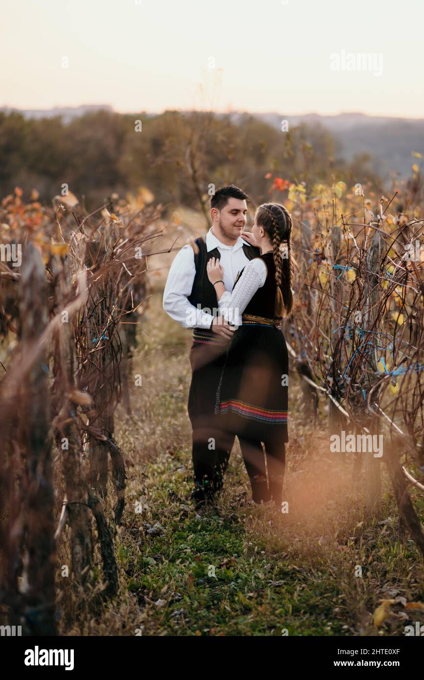 Vertical shot of a Serbian couple in traditional costume having a good ...
