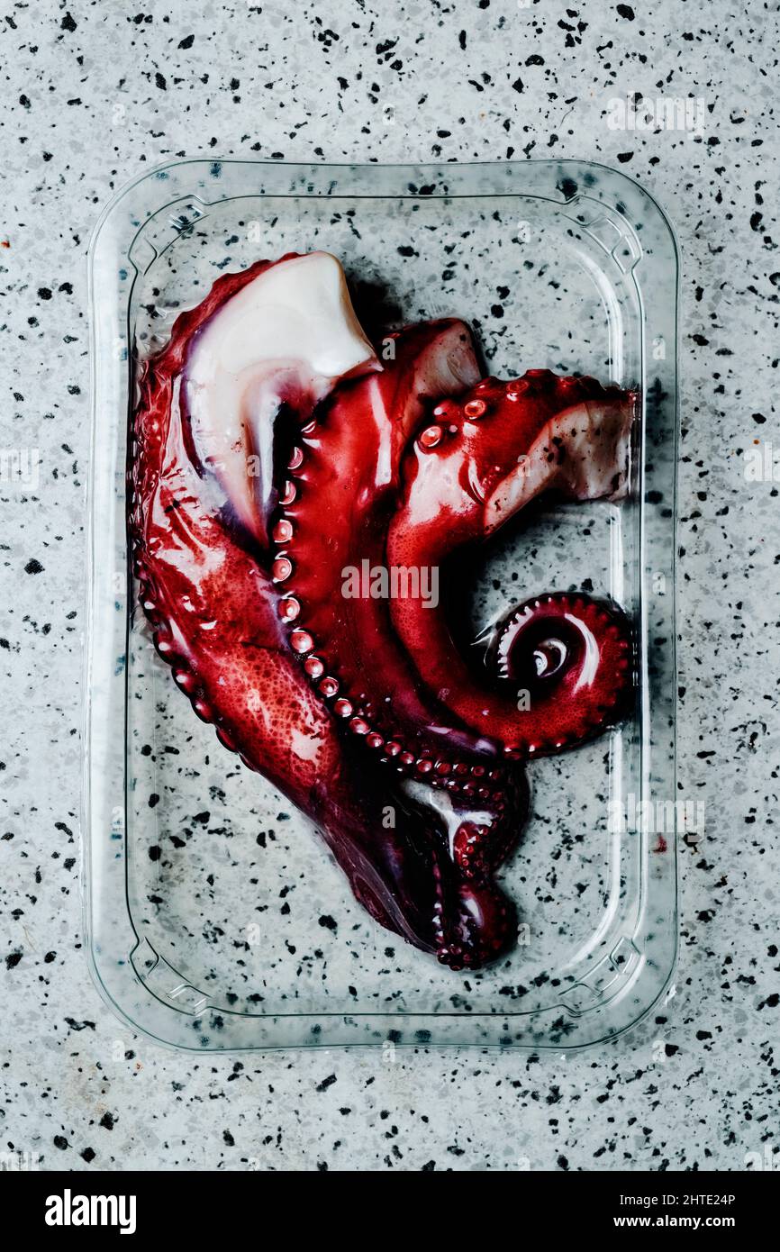 high angle view of some cooked cuts of octopus arms in a plastic tray ...