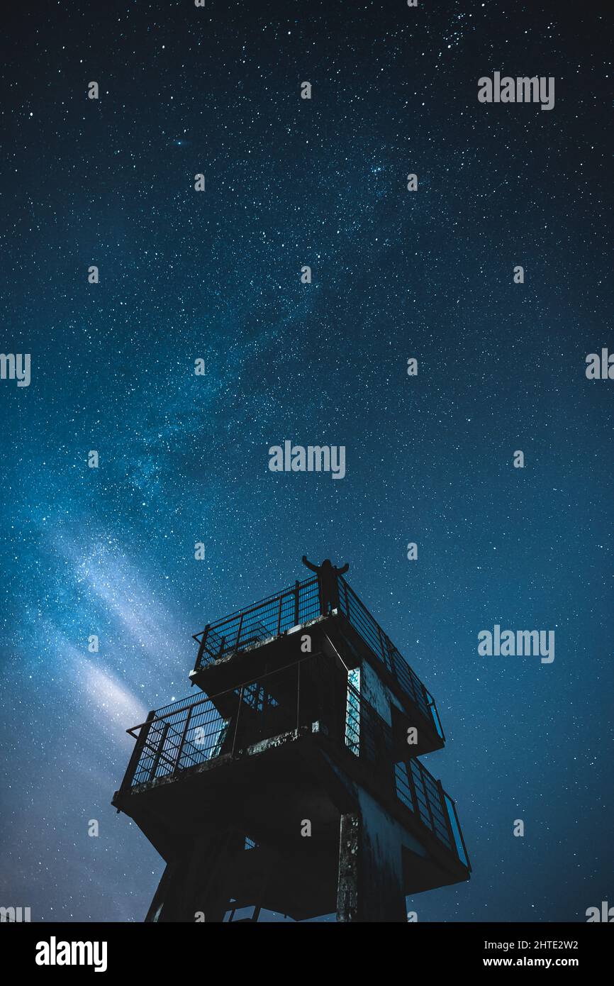 Silhouette of a man on a watchtower enjoying the starry night sky and ...