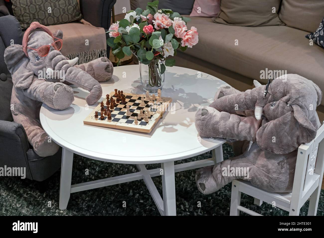 Two plush elephants in glasses play chess at a white table Stock Photo ...