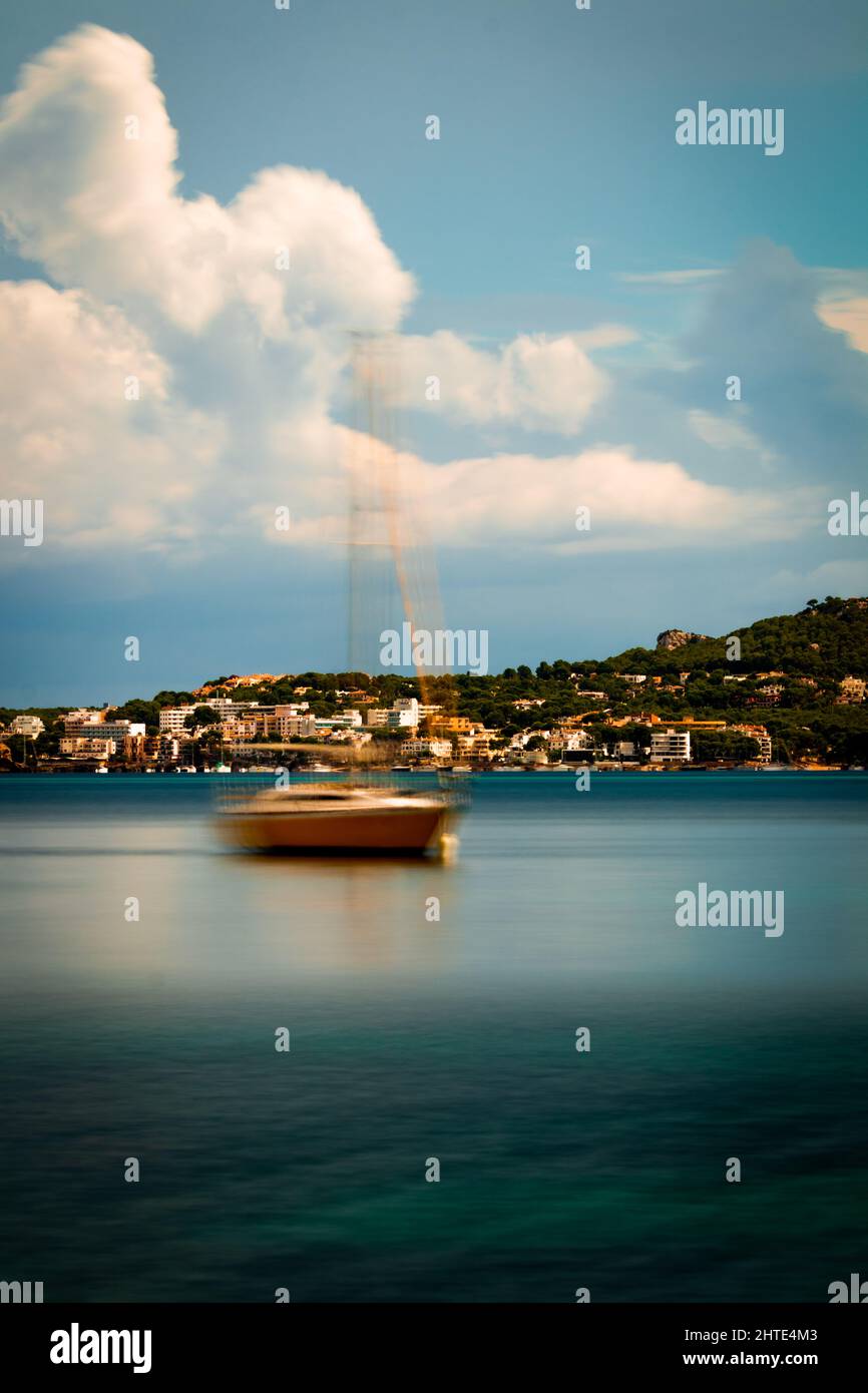 Vertical photo of a lake, a boat and buildings on a forest hill in ...