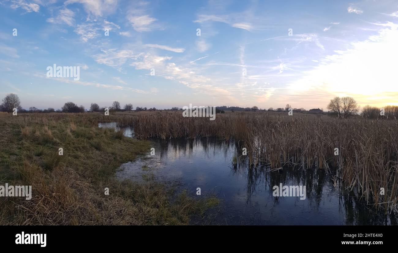 Beautiful sunset sky over a field with a lake Stock Photo - Alamy