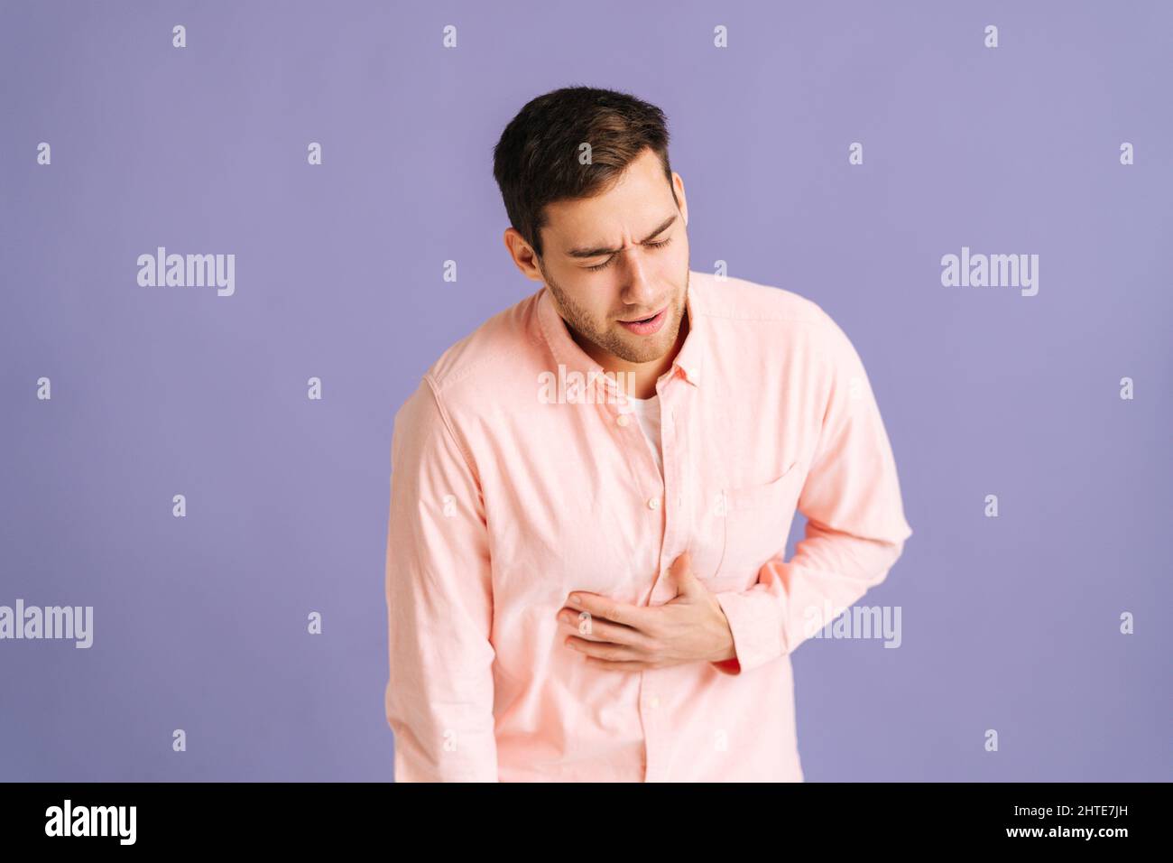 Portrait of unhappy young man feeling sudden stomach pain, severe ...