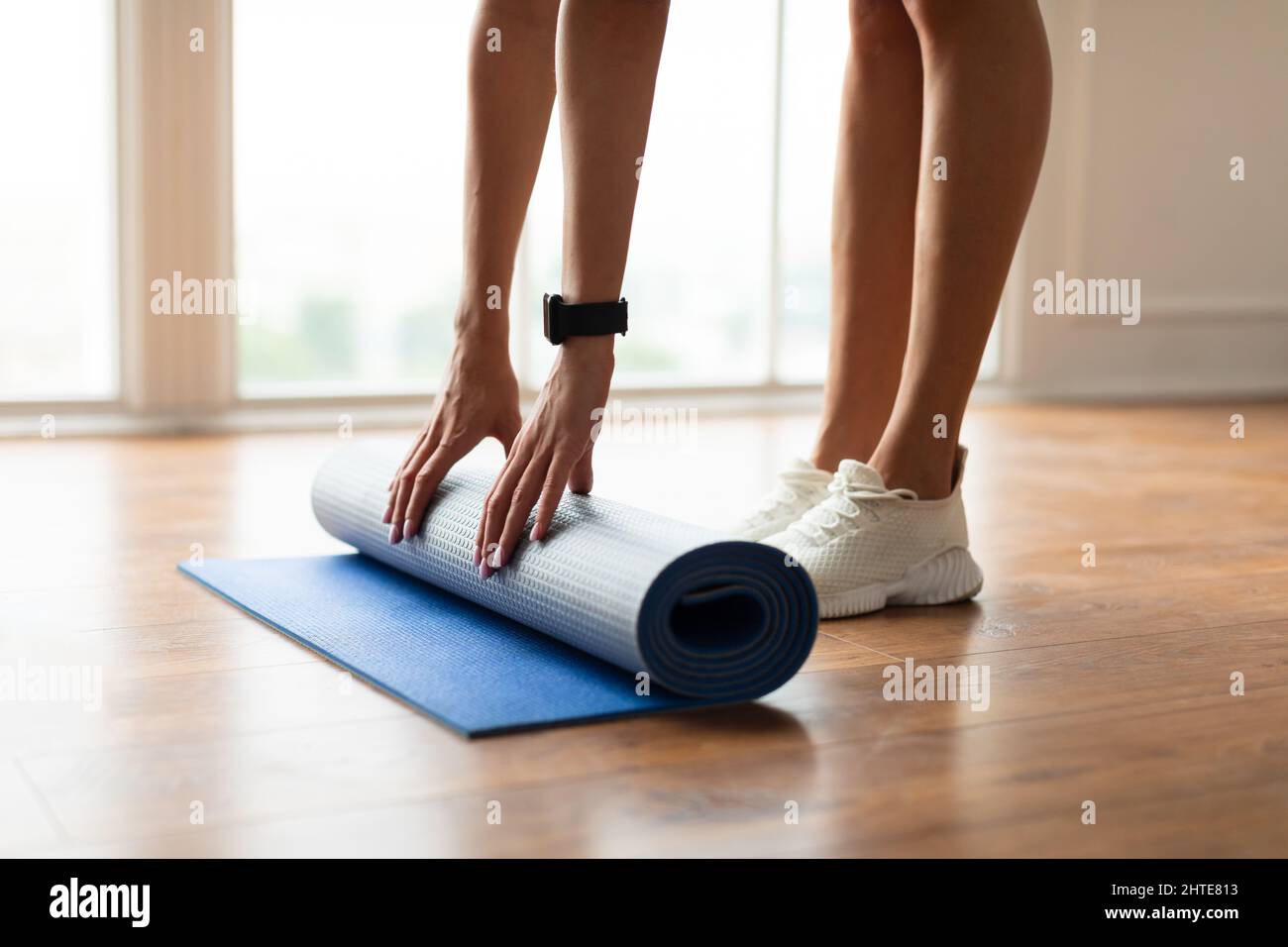 Closeup of young woman unrolling yoga mat on floor Stock Photo - Alamy