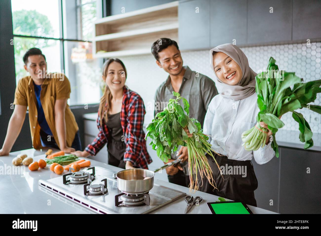 Good friends laughing and talking while preparing meals at table for ...