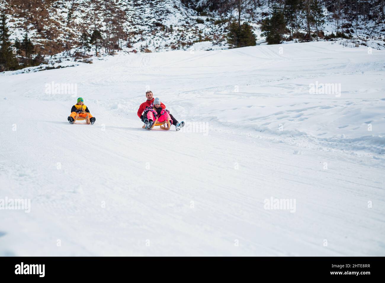 Cheerful Caucasian boy and girl enjoying with father in winter play ...