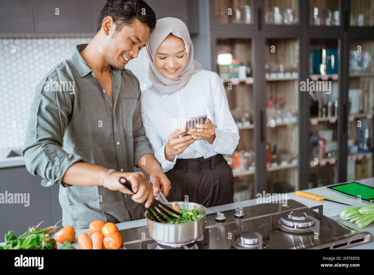 muslim couple cooking together in the kitchen while look at video Stock ...