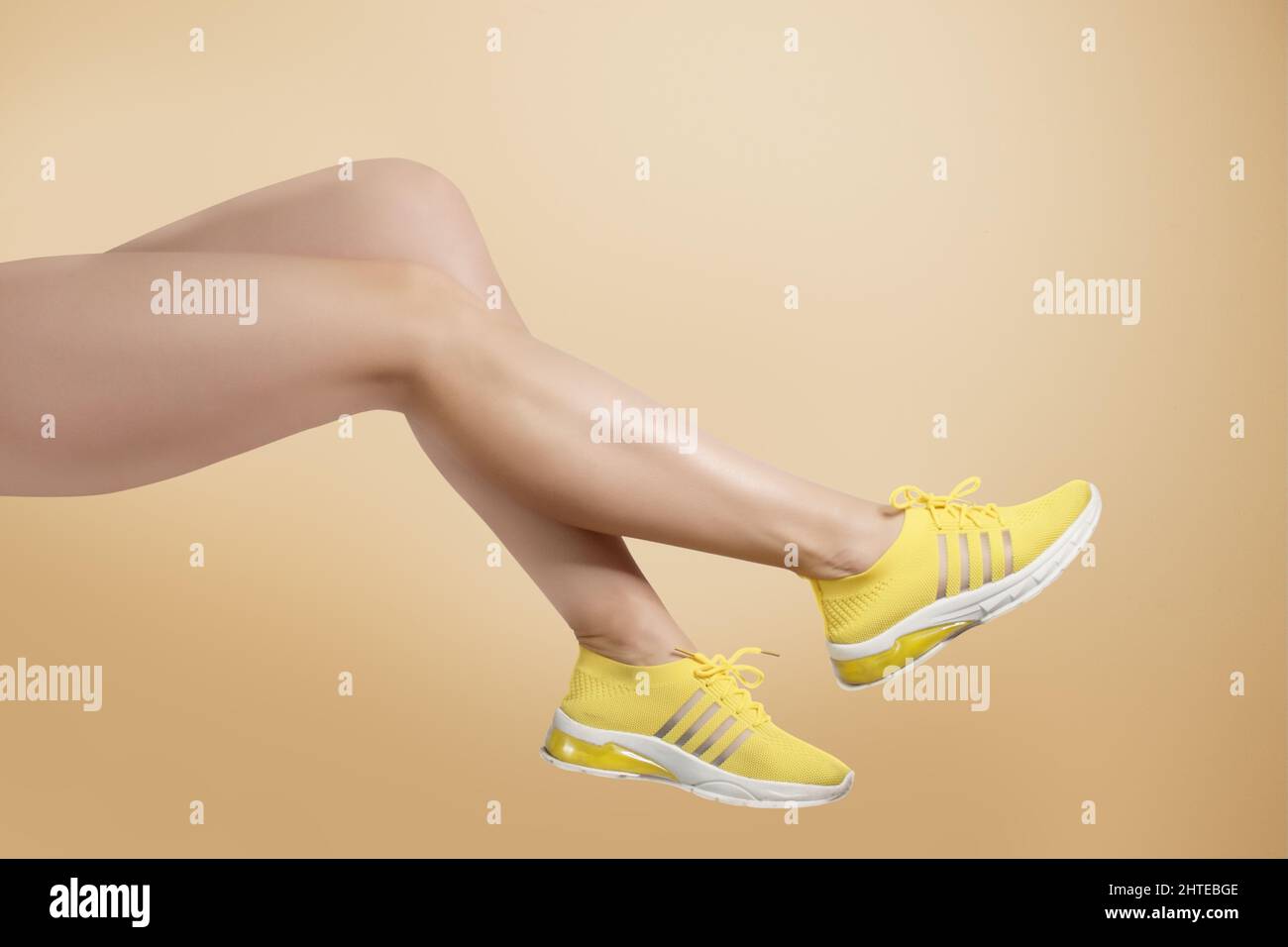 Studio shot of a young woman's legs in a pair of yellow sport shoes for ...