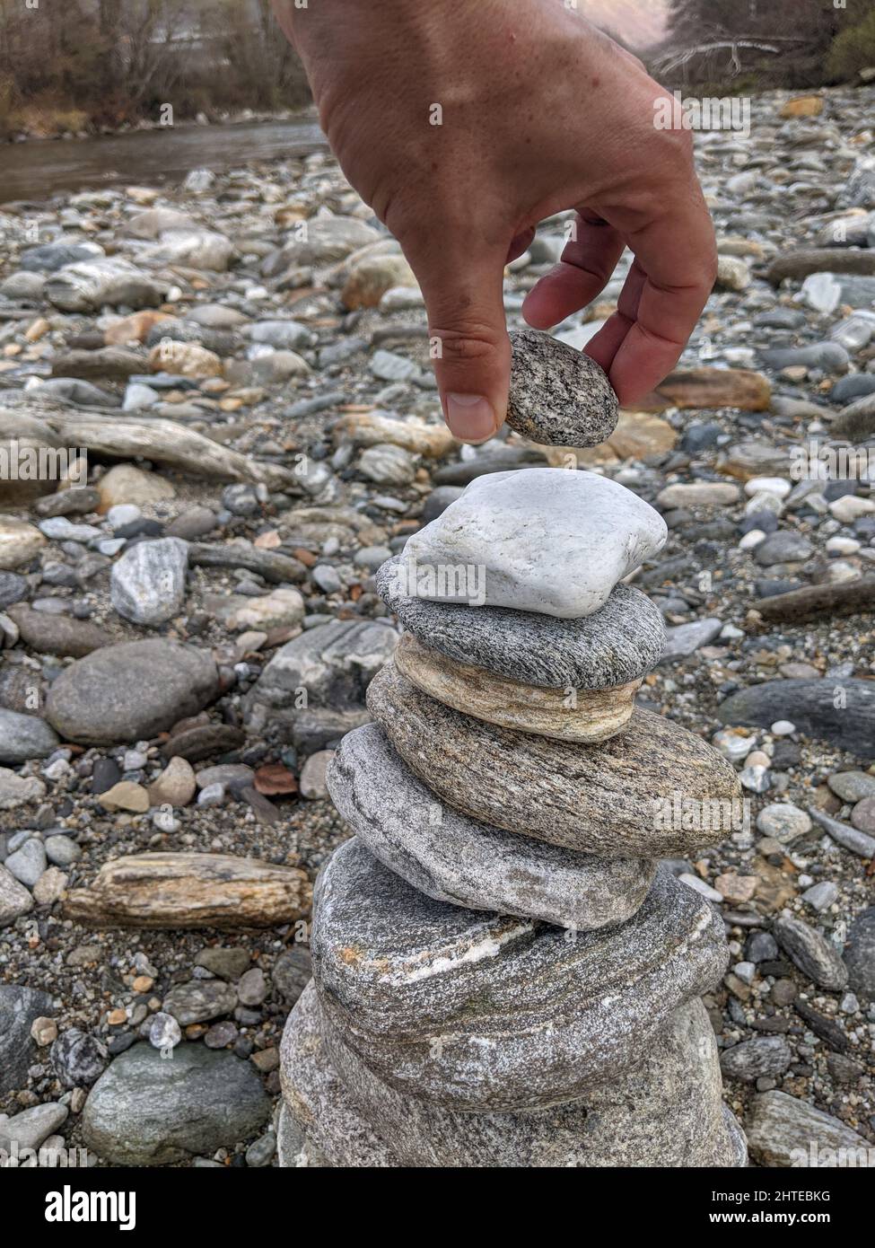 Closeup of a hand putting pebbles on one another on a rocky beach Stock ...