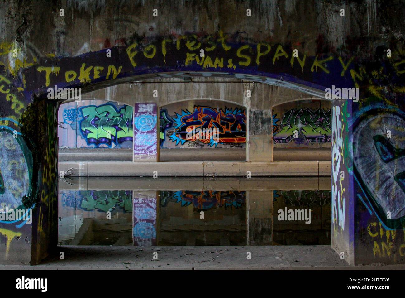 Colorful graffiti on a concrete wall under a bridge over a river Stock ...