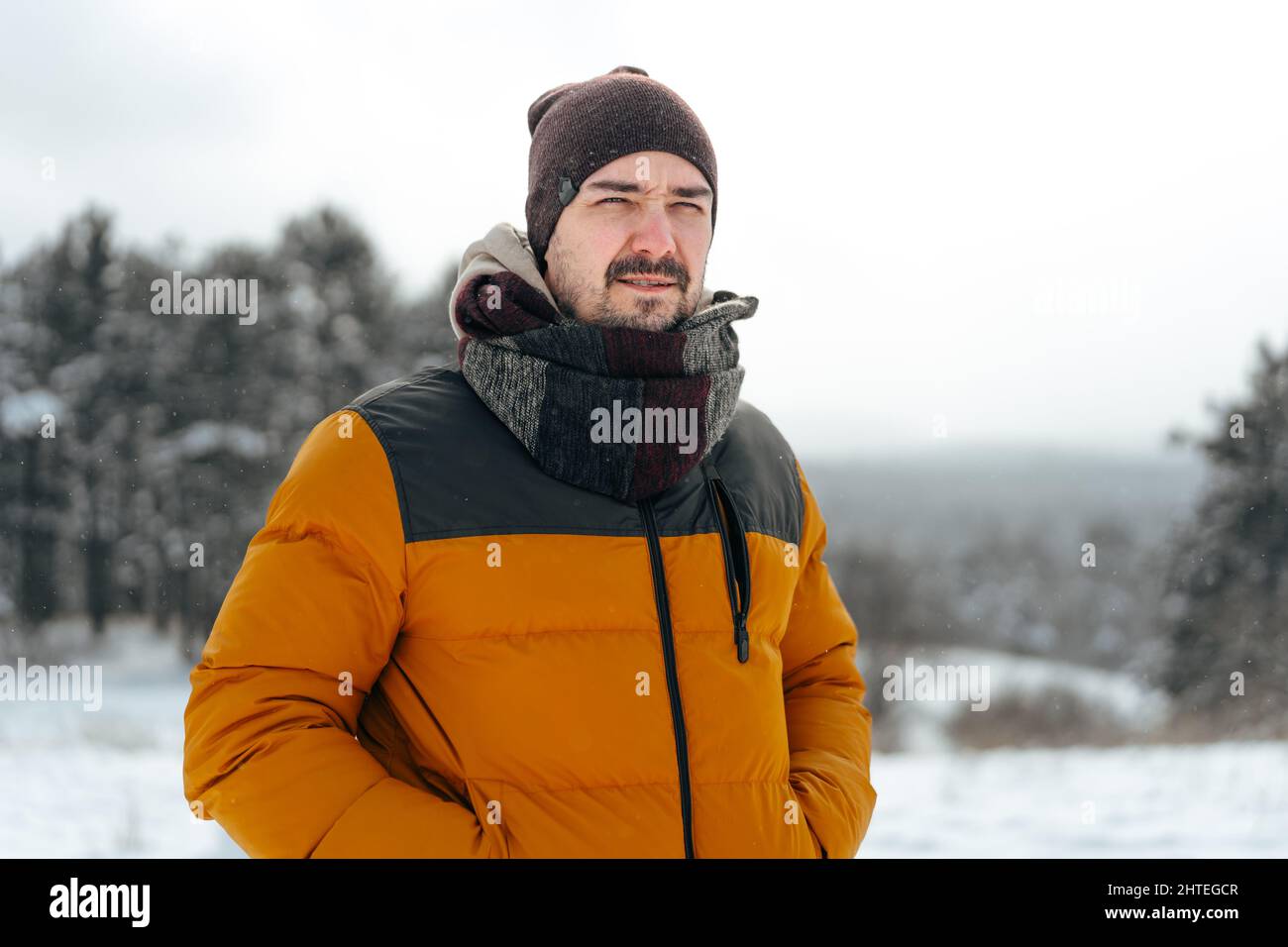 Young man in warm coat standing in snowy winter forest Stock Photo - Alamy
