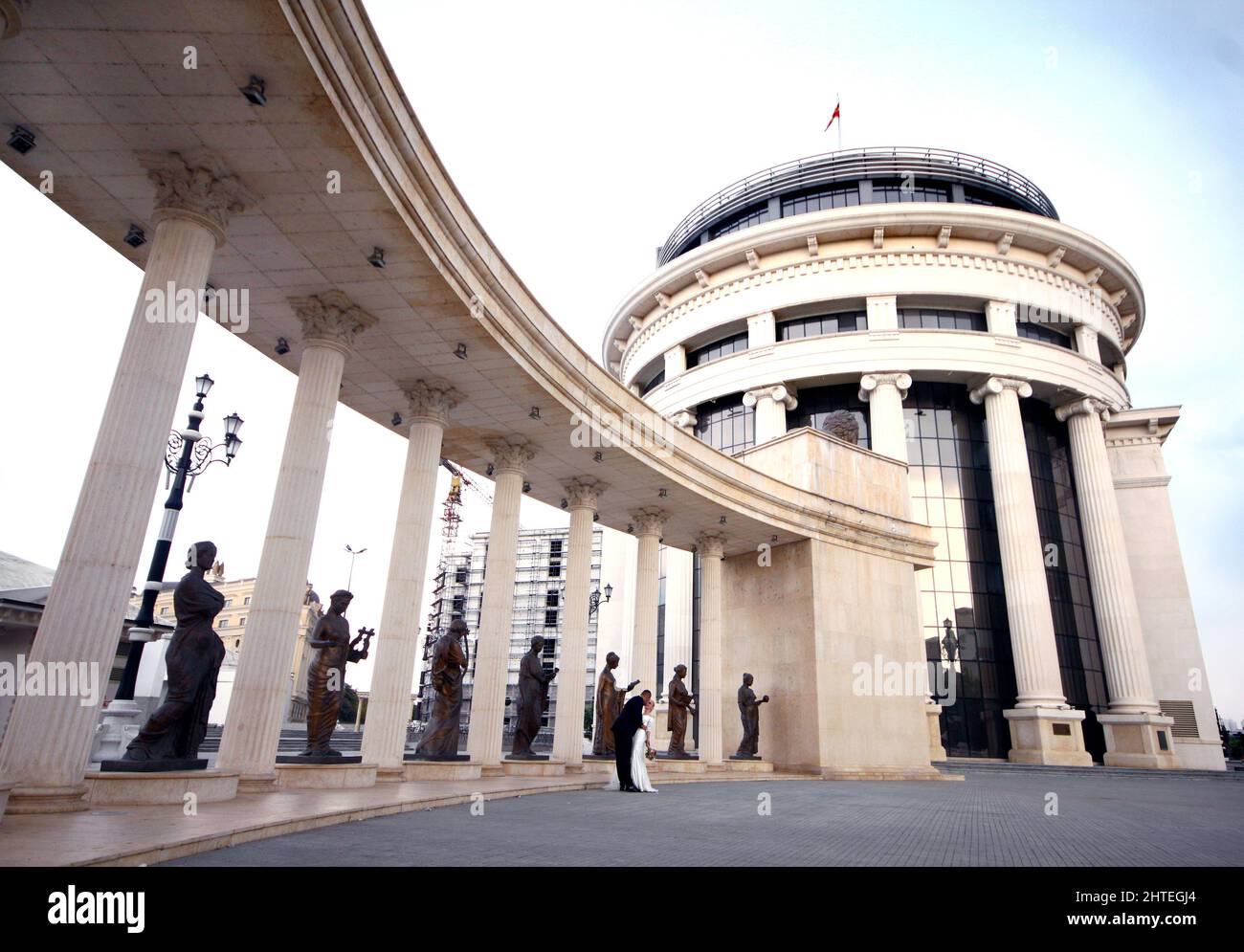 A groom and bride in front of a huge building with a round dome and ...