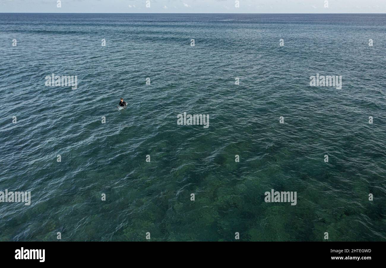 An aerial top view of a male surfer swimming in a tranquil water Stock ...
