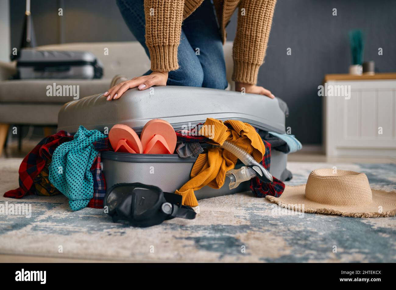 Woman trying to close overload travel suitcase Stock Photo - Alamy