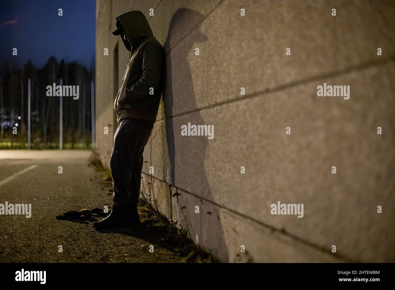 Lonely man in a jacket on a street while leaning on the wall Stock ...