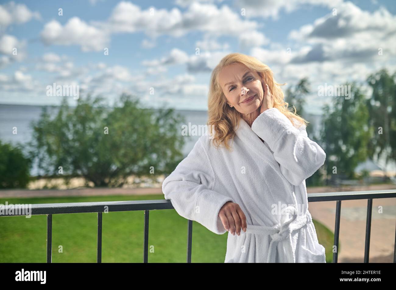 A blonde woman in a white robe standing at the balcony Stock Photo - Alamy