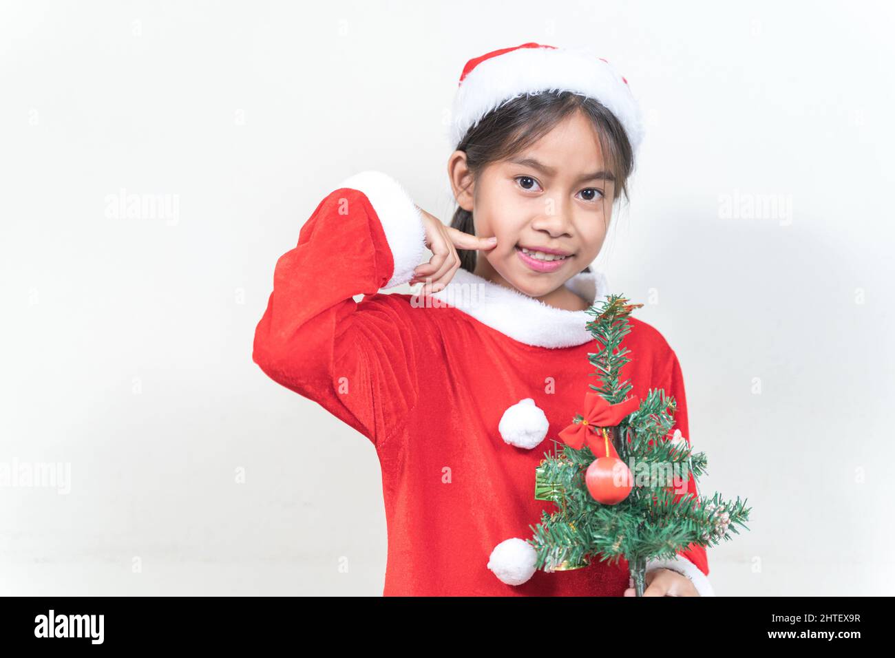 Cute Thai girl with Santa costume touching her cheek and holding a ...