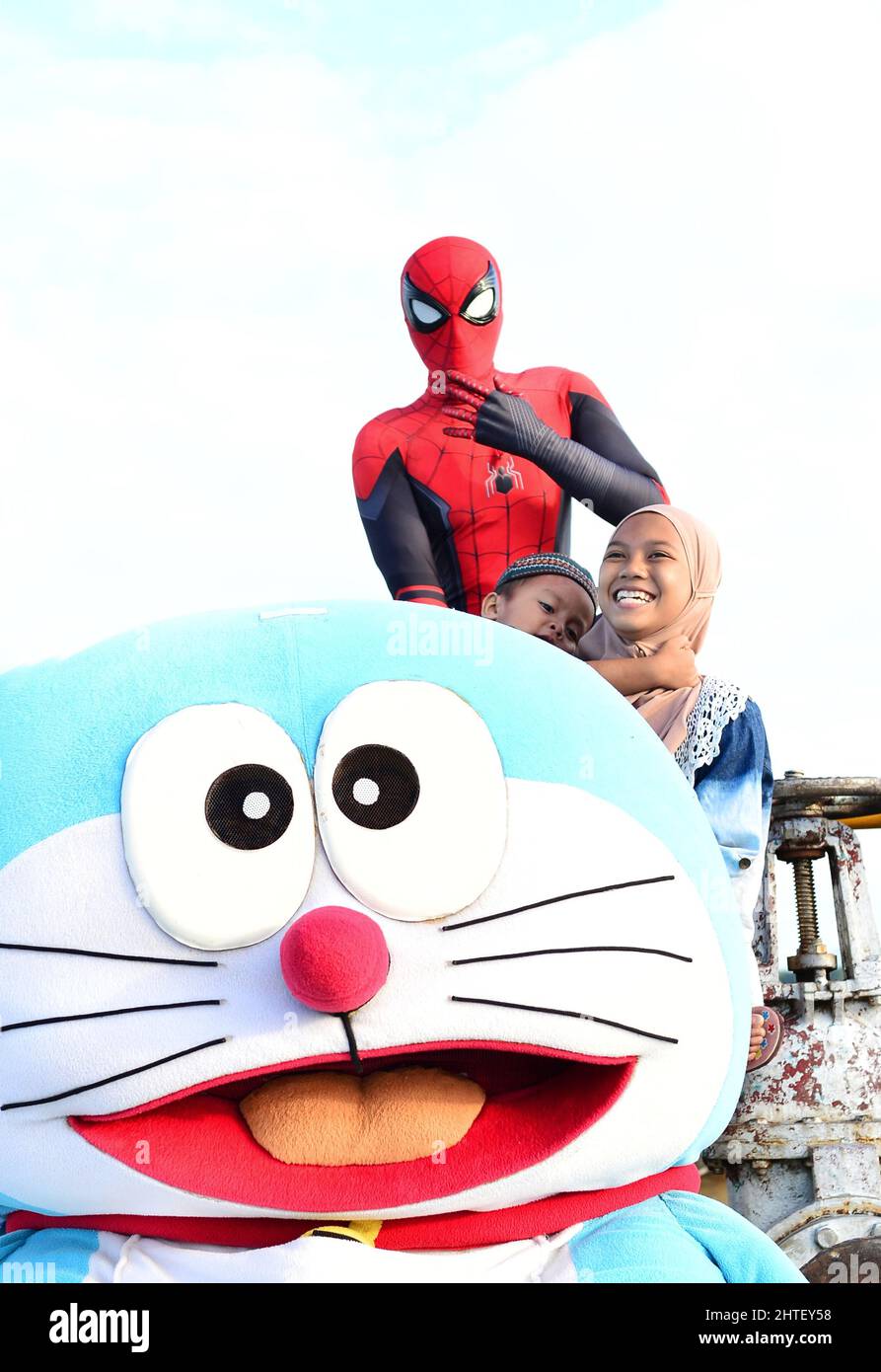 Vertical shot of a mother and her son posing near people in spiderman ...