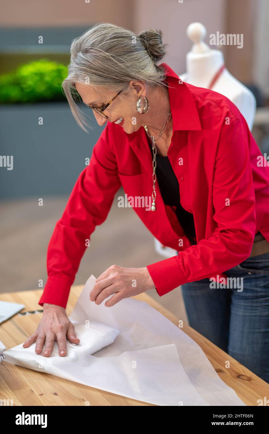Woman standing sideways to camera wrapping clothes in paper Stock Photo ...