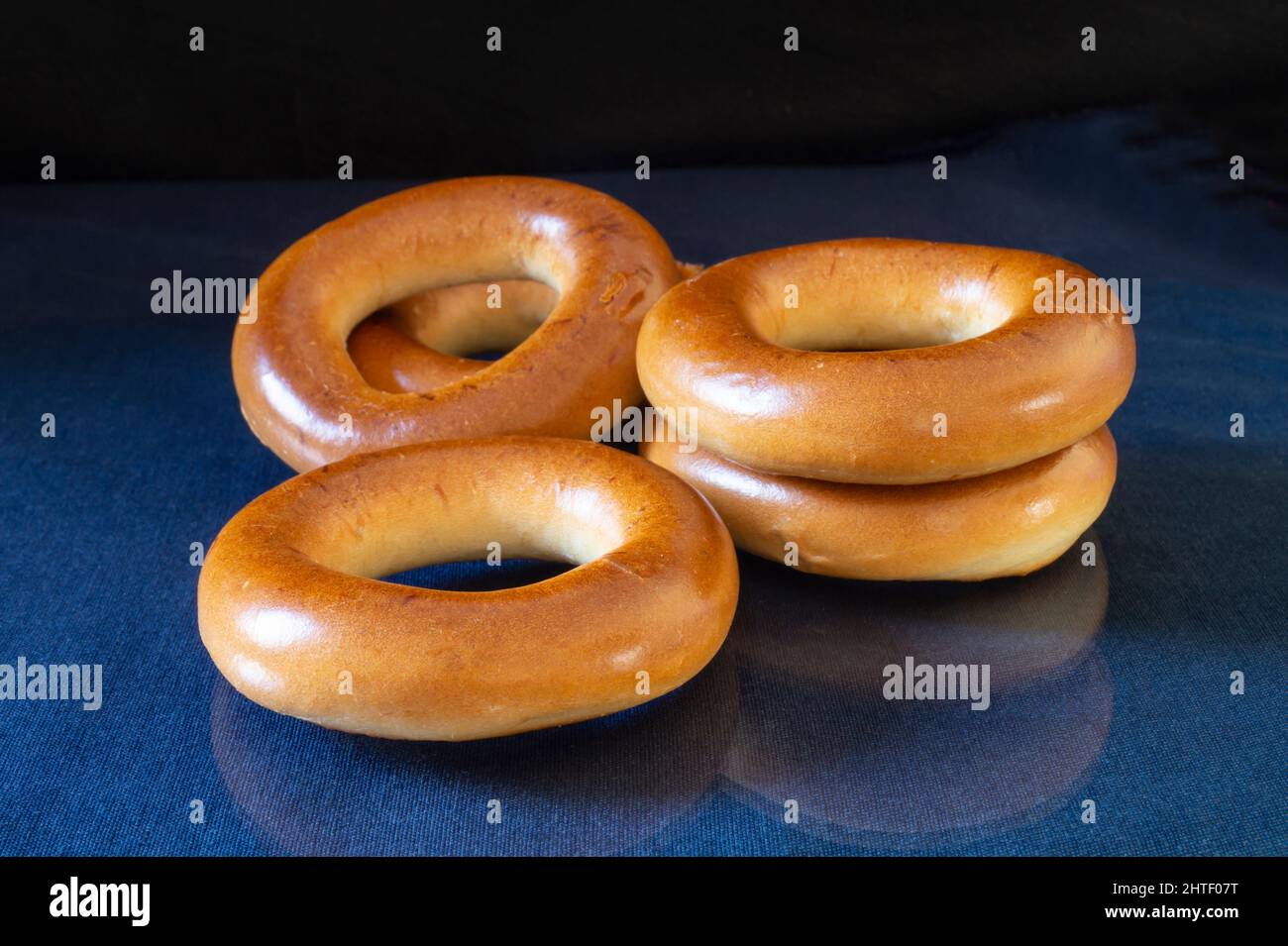 Round bagel on a blue table with reflection, Food on a black background ...